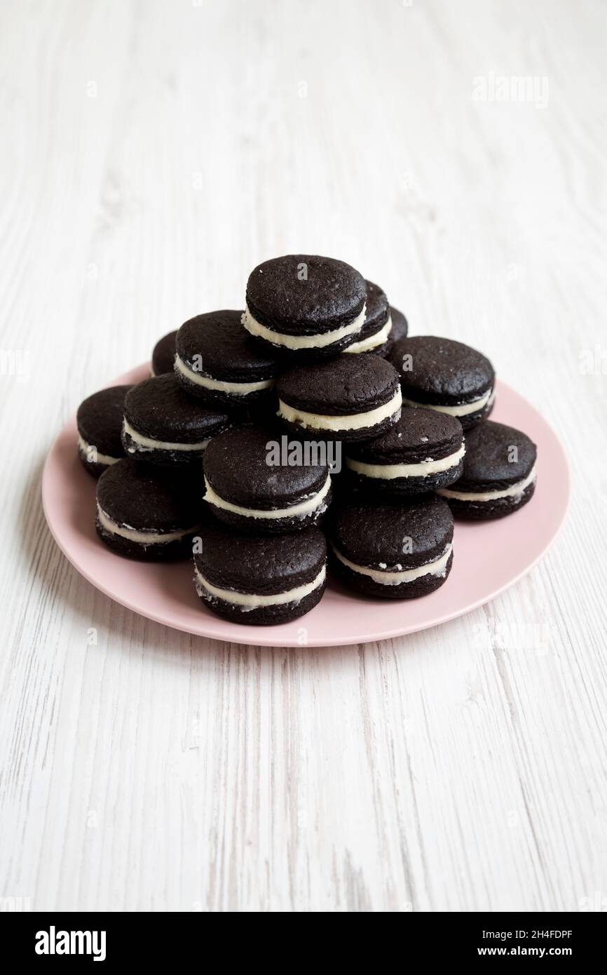 Homemade Oreos on a pink plate on a white wooden background, side view ...