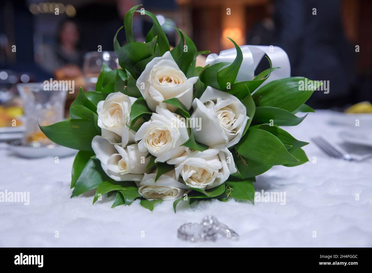 Wedding engagement rings on the background of a beautiful bouquet of roses . Stylish white ...