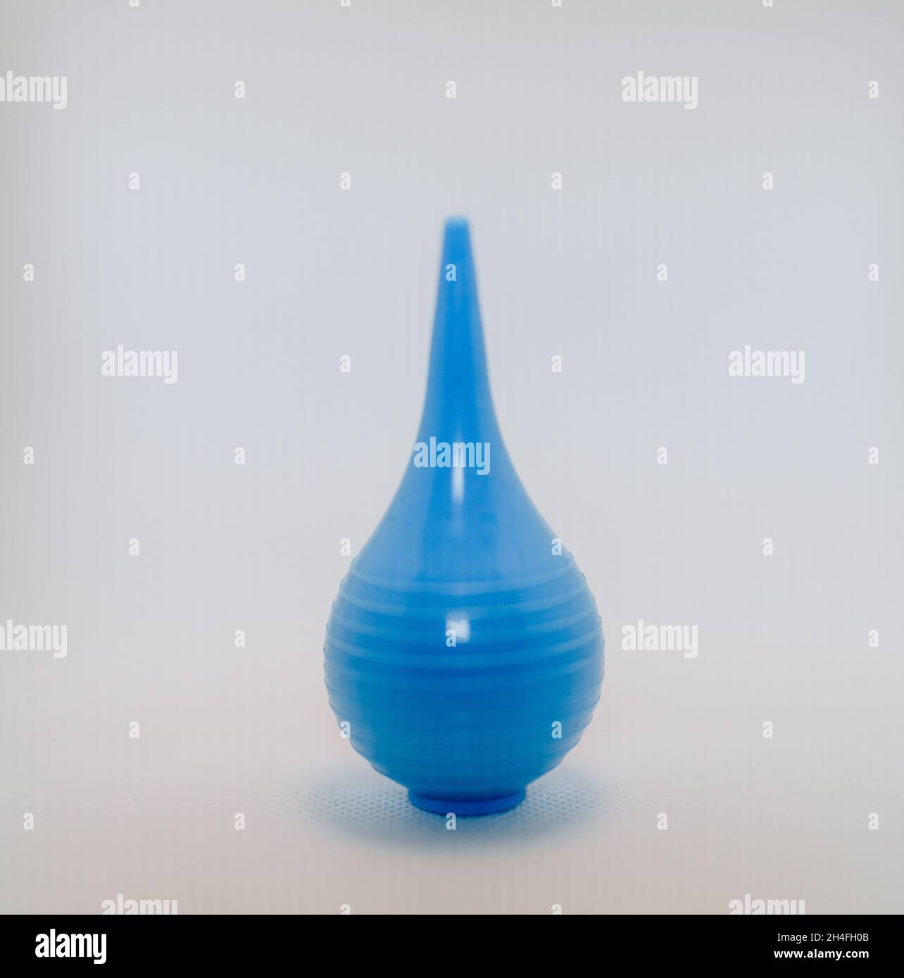 Vertical closeup of a blue ear washing syringe on a white background ...