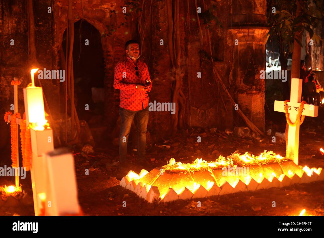A catholic family member offers prayers for the dead at a Dhaka ...