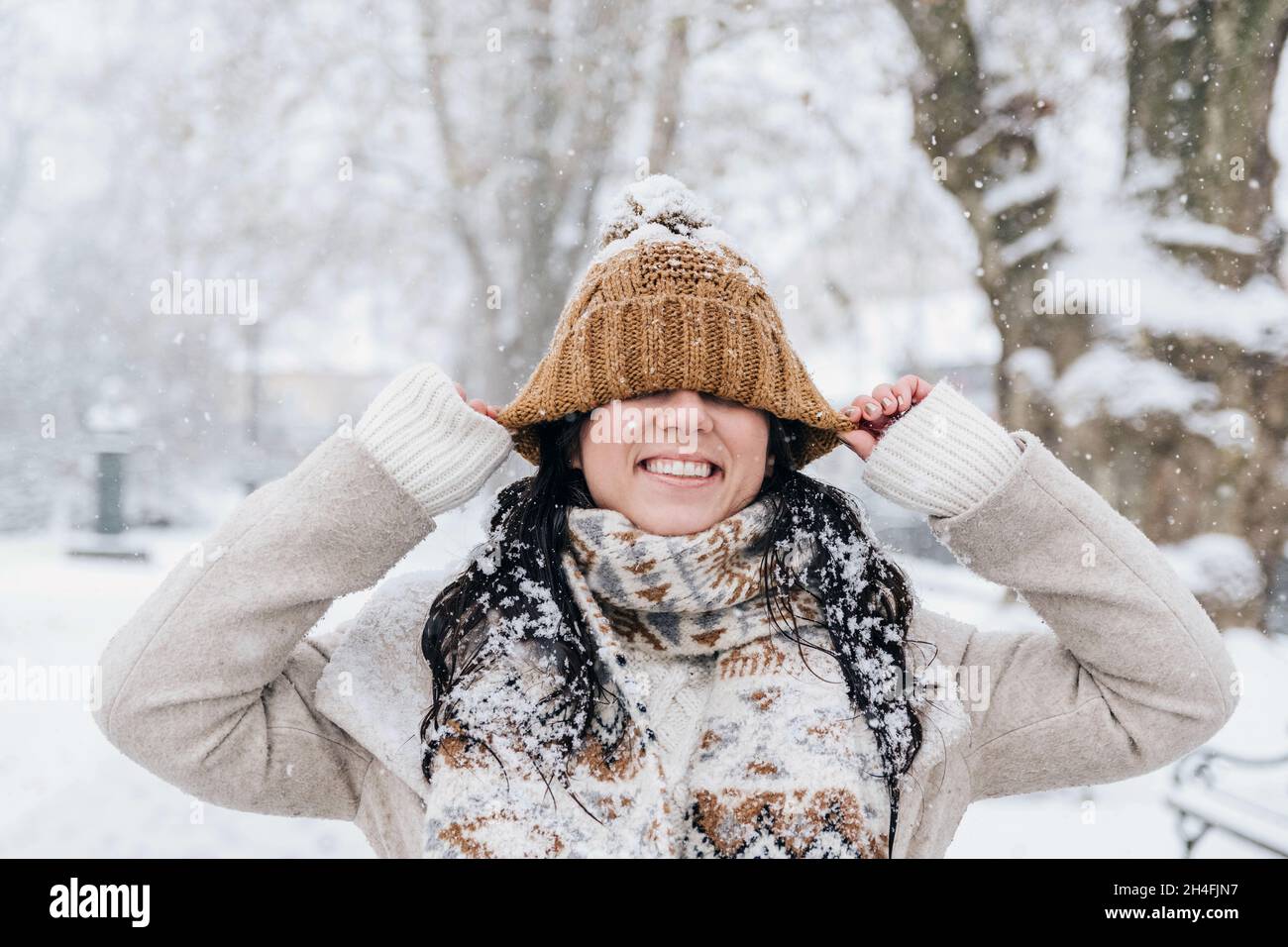 Portrait of beautiful young woman in winter clothes pulling her hat ...