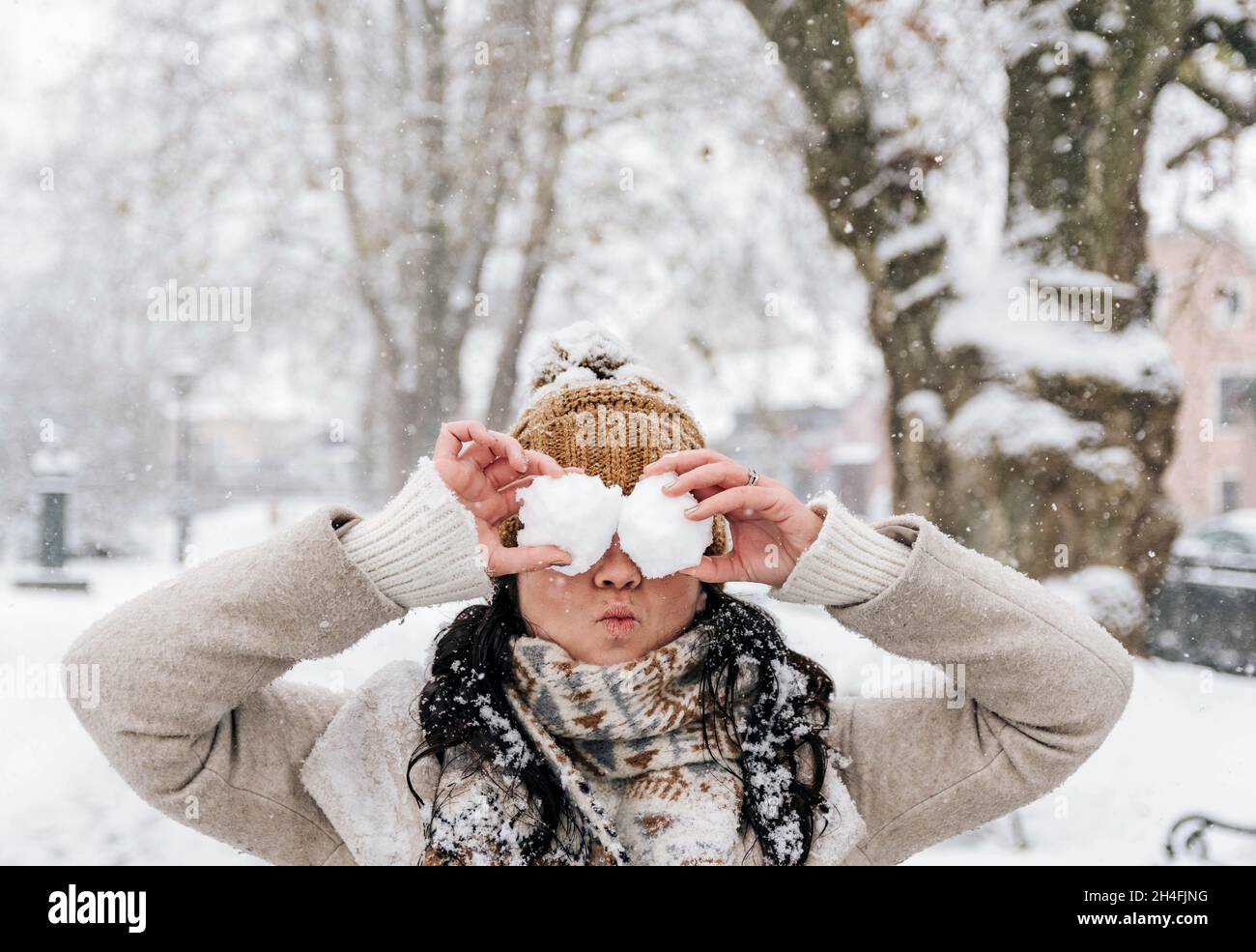 Winter portrait of beautiful young woman holding snowballs in front of ...