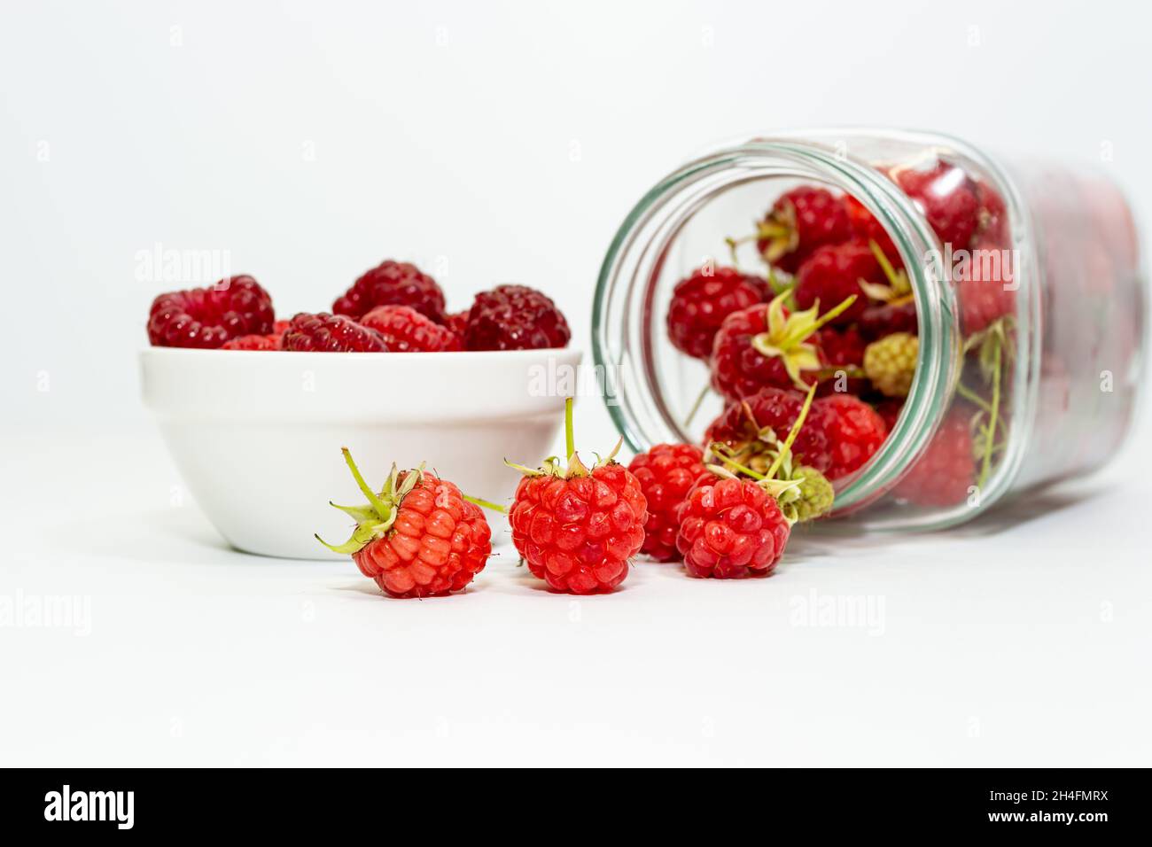 Freshly picked red raspberries in a small bowl and in an inverted glass ...