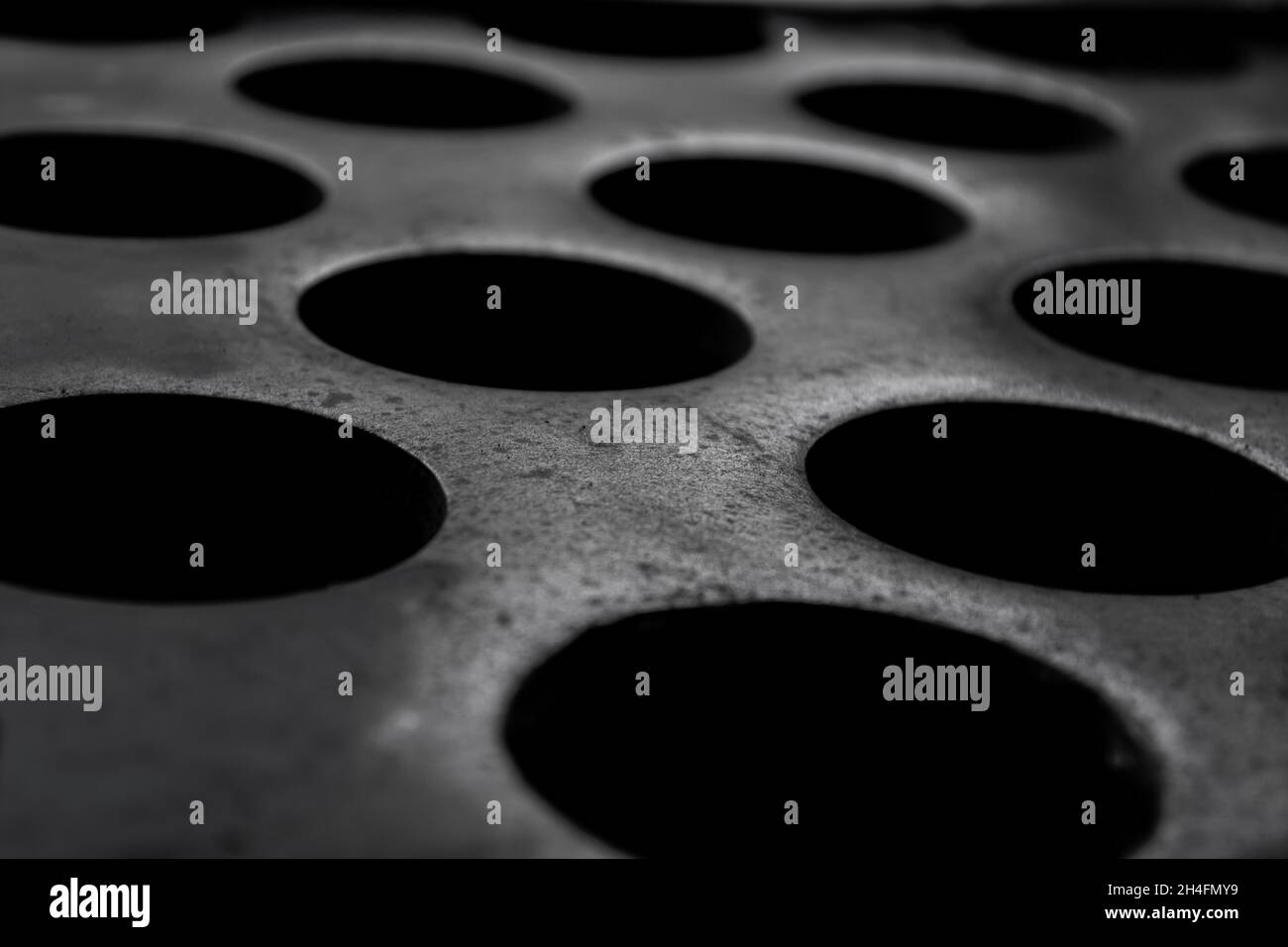 Round black holes in an old metal surface close-up. Selective focus ...