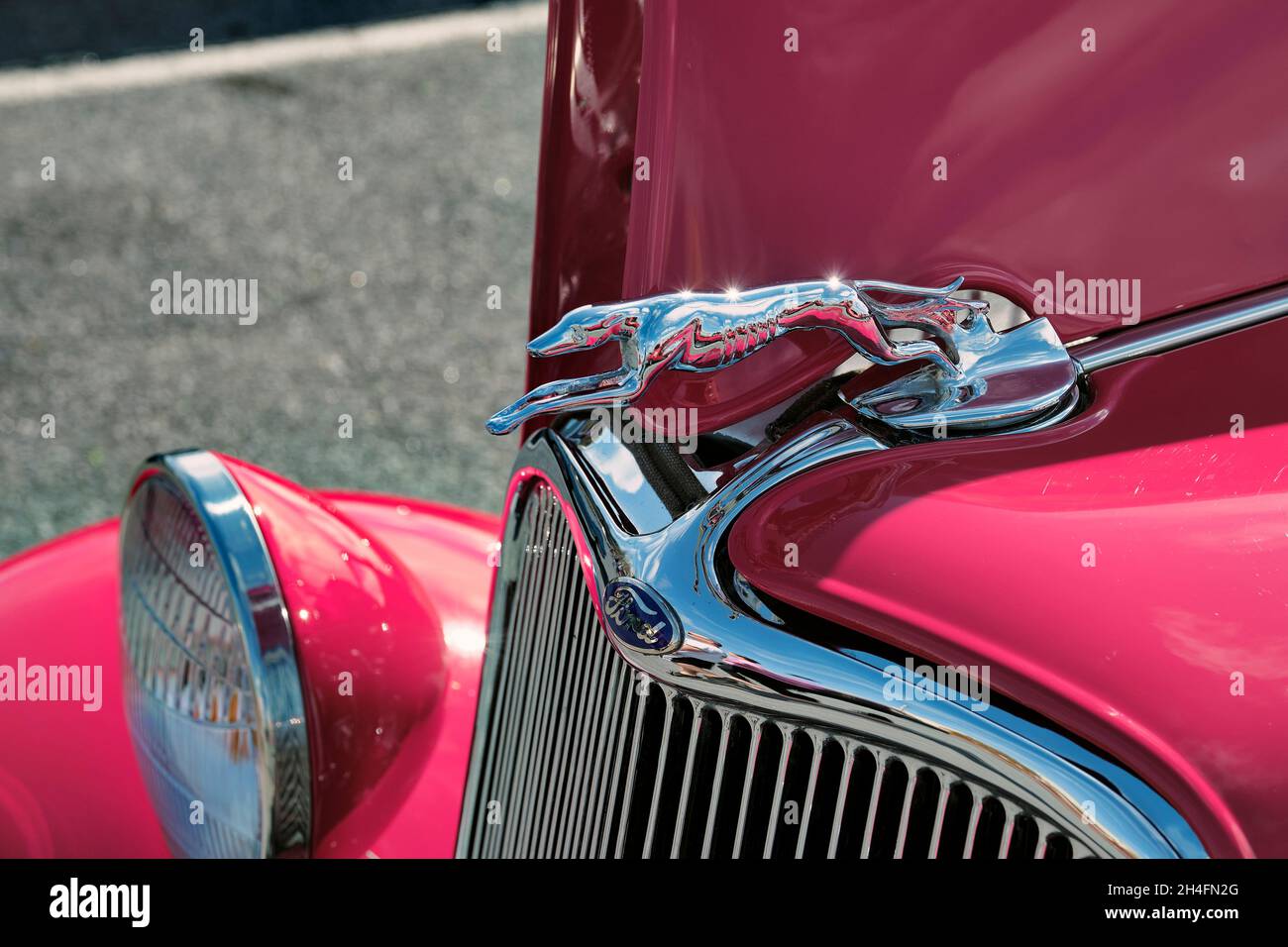 A chrome greyhound adorns the hood of a red custom car at the 2021 ...