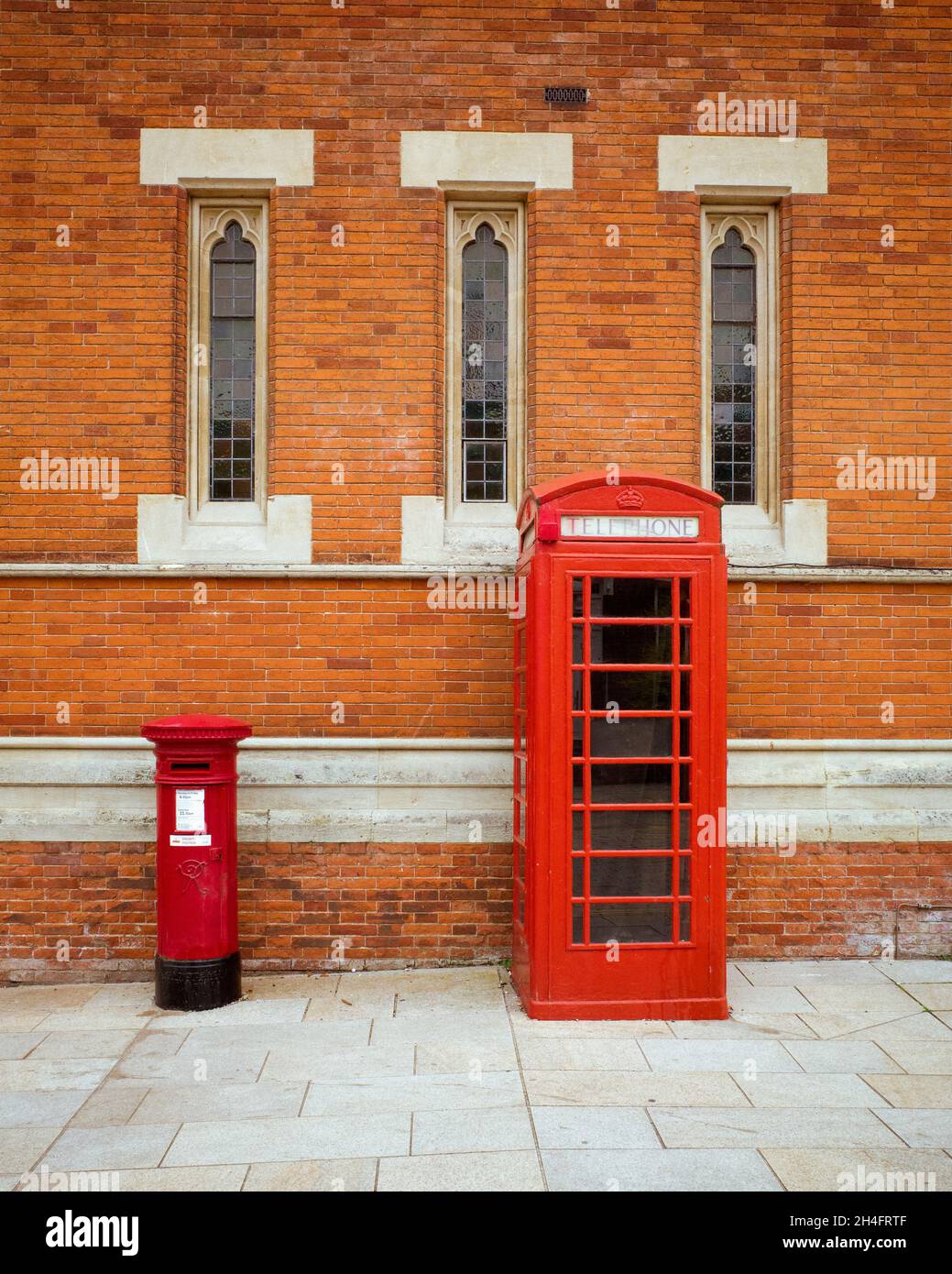 A red post box and telephone box stand next to each other on a street ...