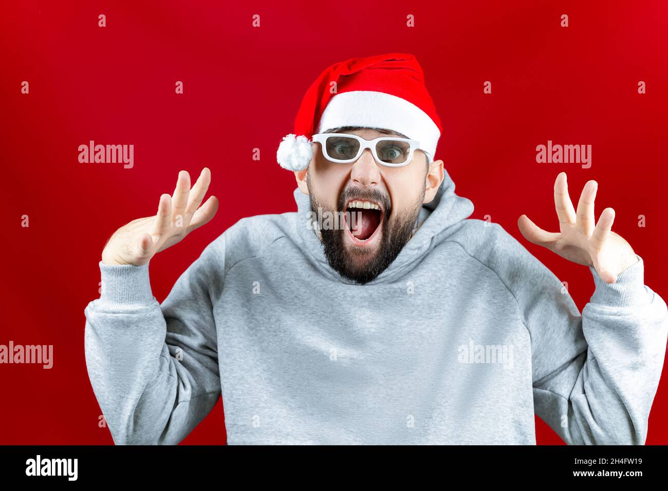on a red Christmas background, a man in a Santa Claus hat and with ...