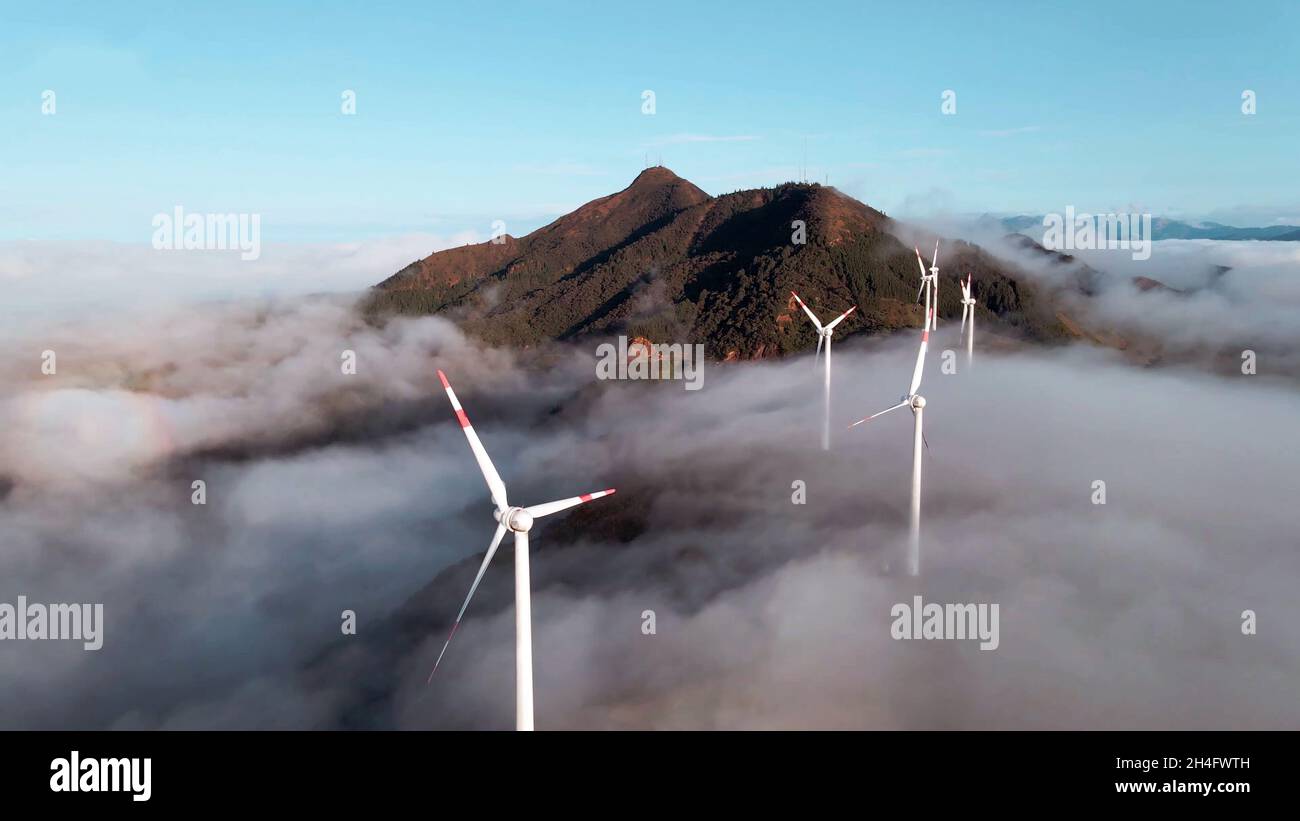 aerial view from a drone of a wind turbine farm above the clouds with a ...
