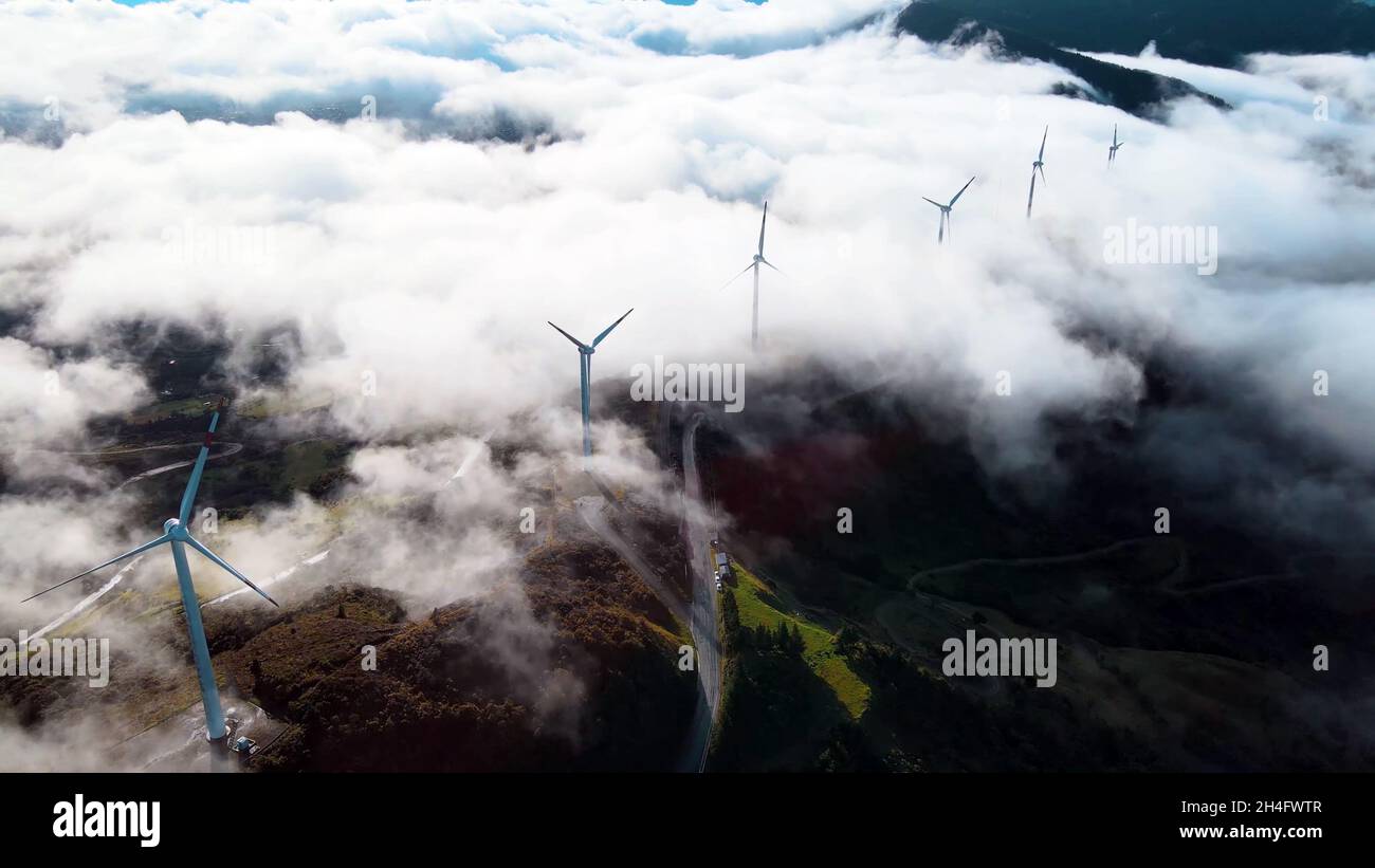 Aerial view from a drone of a wind turbine farm above the clouds and ...