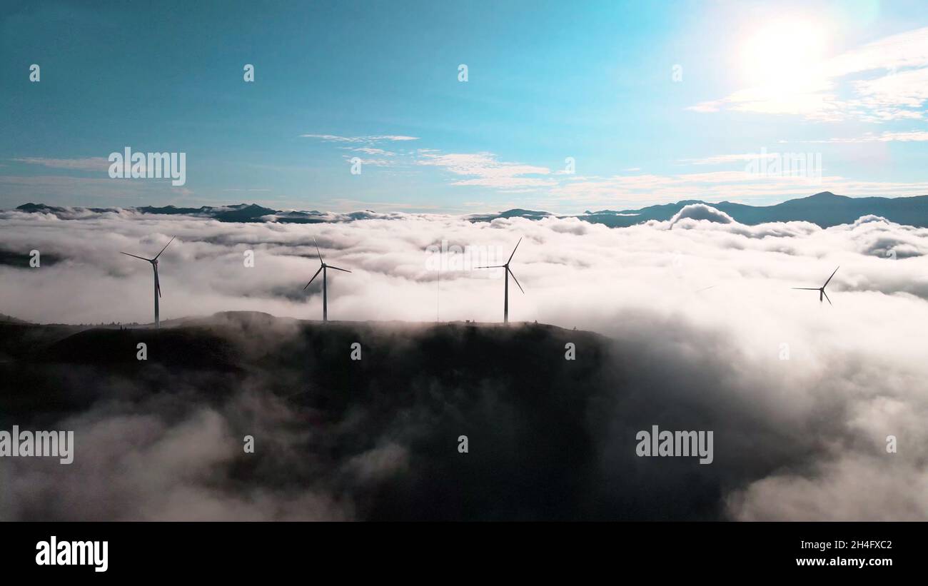 aerial view from a drone of a wind turbine farm silhouetted above the ...