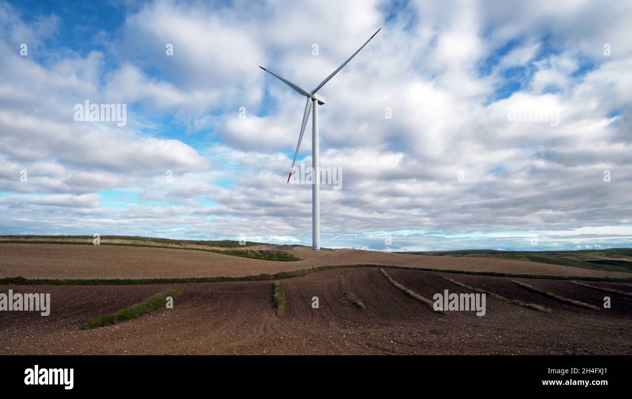view from the ground of a wind turbine in the middle of a field of dirt ...