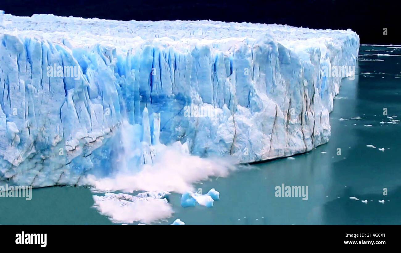 drone view of a chunk of glacier ice breaking off and falling into the sea water due to melting ...