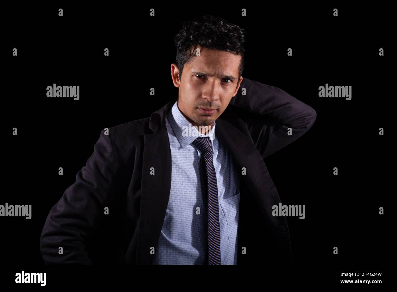 Young latin businessman posing with front view, isolated on black ...