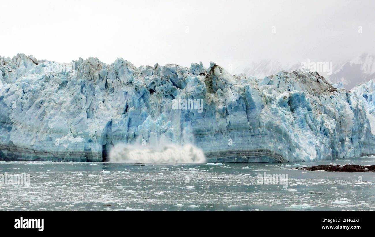 front view of a large chunk of glacier ice breaking off and falling ...