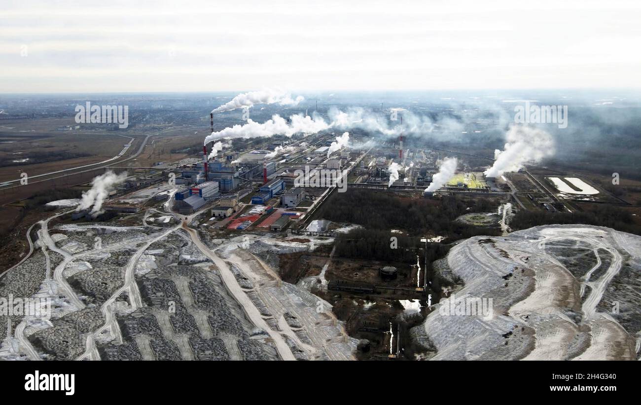 drone view of an open pit mine with many chimneys spewing smoke and ...