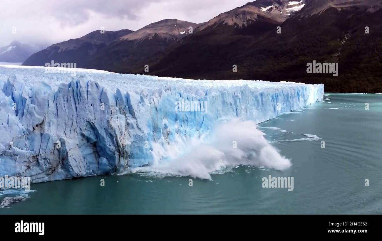 view from a drone of a piece of glacier ice breaking off and falling ...