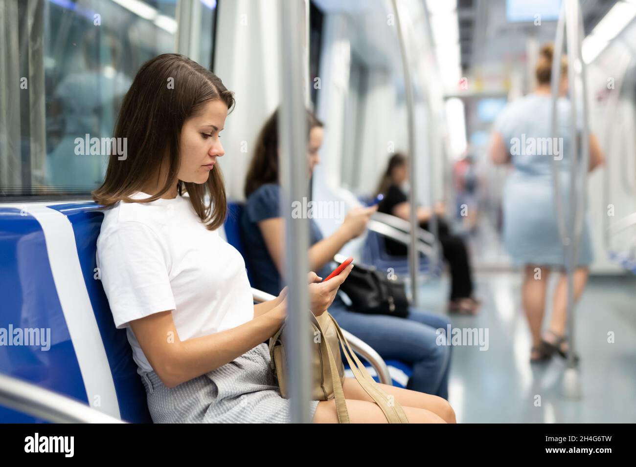 Positive woman reading from mobile phone screen in metro Stock Photo ...