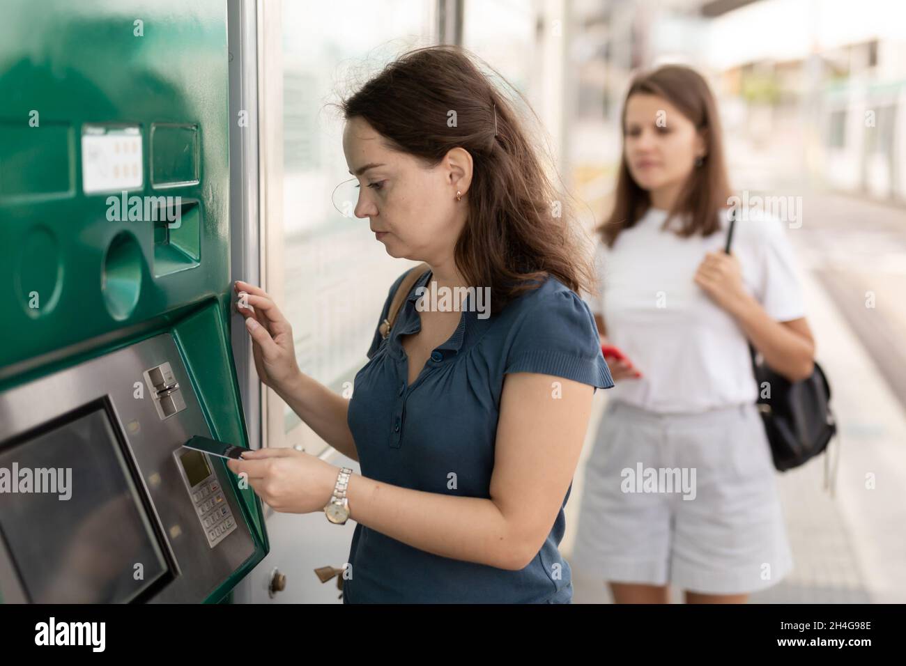 Woman using ticket vending machine at tram stop Stock Photo - Alamy