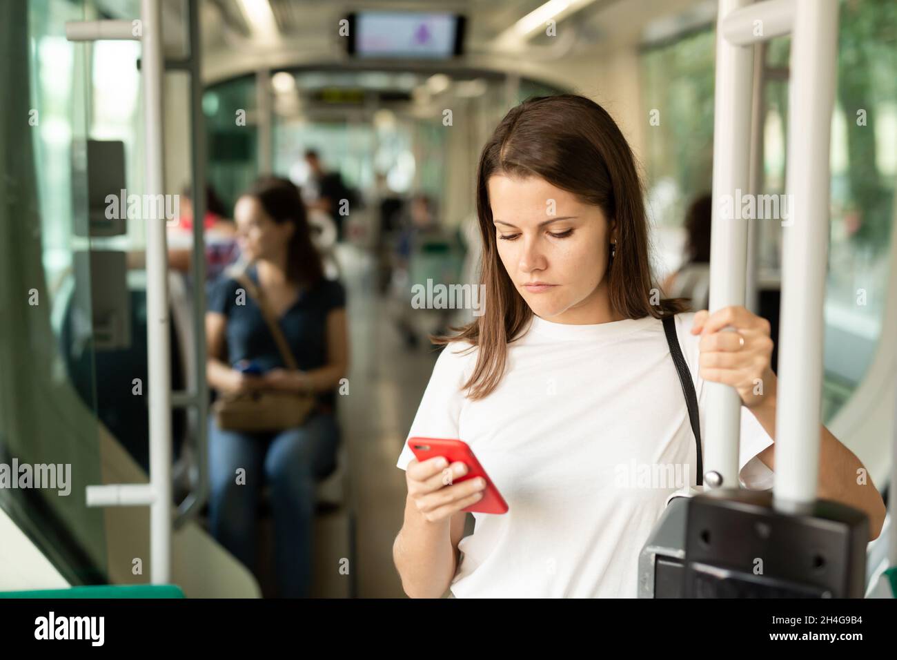 Woman using phone in public transport Stock Photo - Alamy