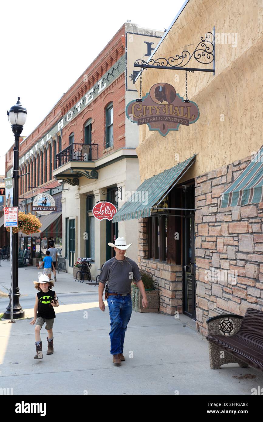A man in cowboy hat open carry a gun walking on street with his child ...