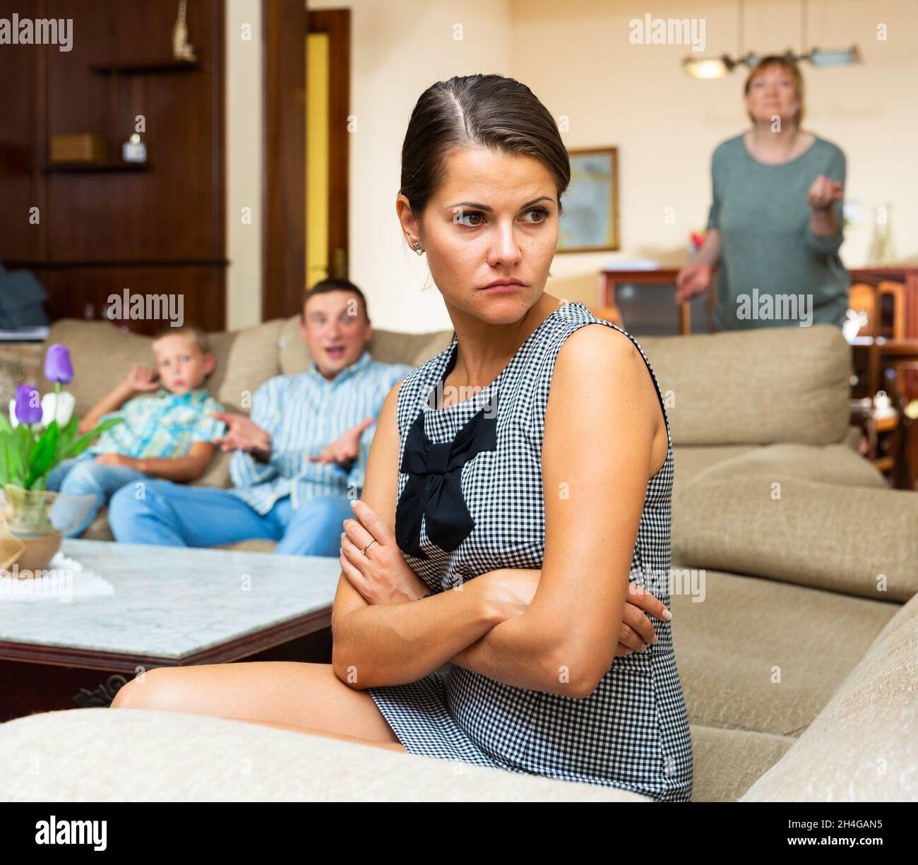 Upset woman sitting during quarrelling between family on background ...