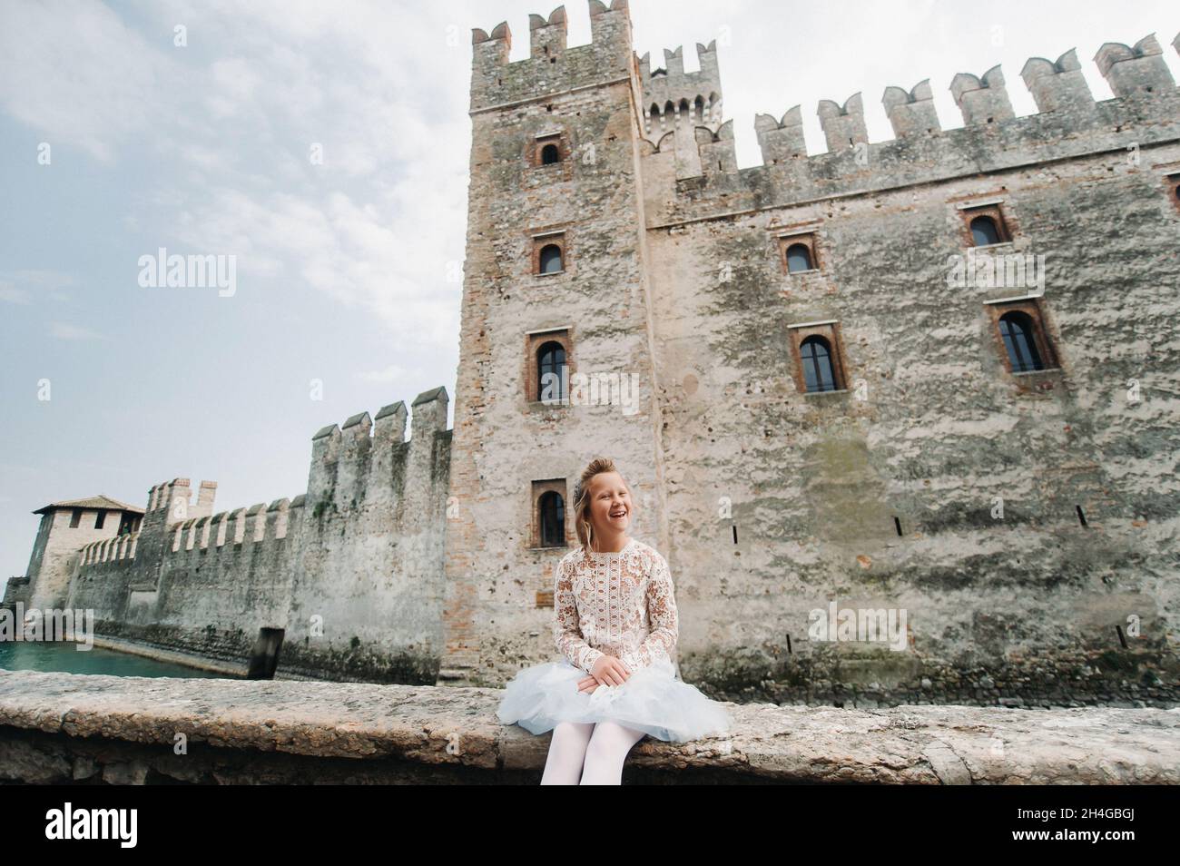 a little girl in a white dress on the background of the old castle in ...