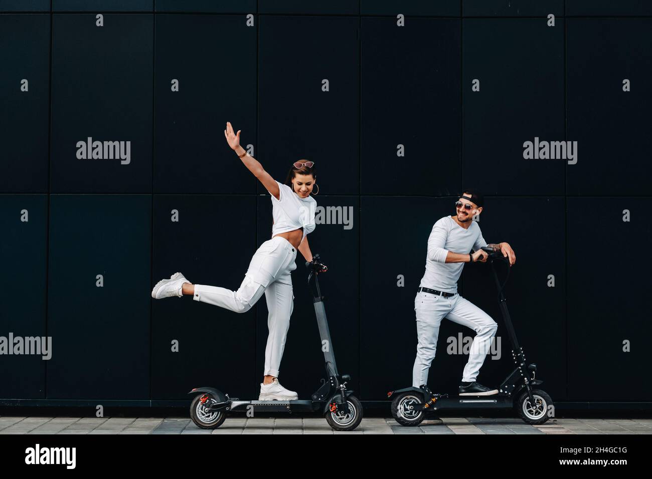 A girl and a guy are walking on electric scooters around the city, a ...