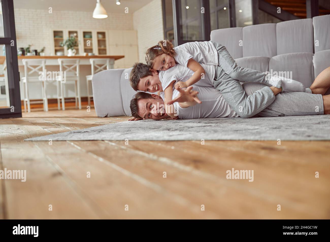 Funny dad with kids on back in living room Stock Photo - Alamy