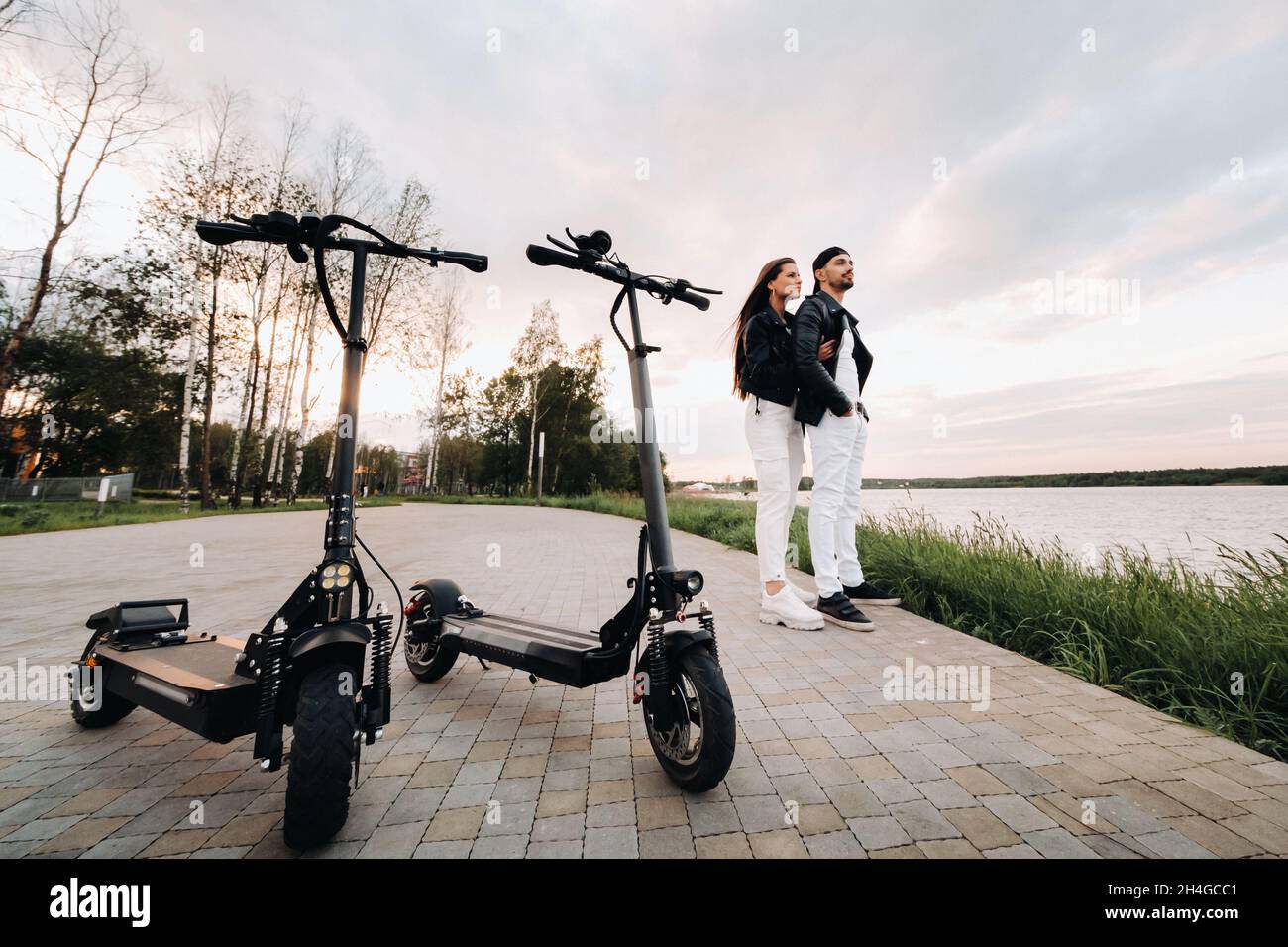 portrait of a couple sitting near electric scooters, enjoying time in ...