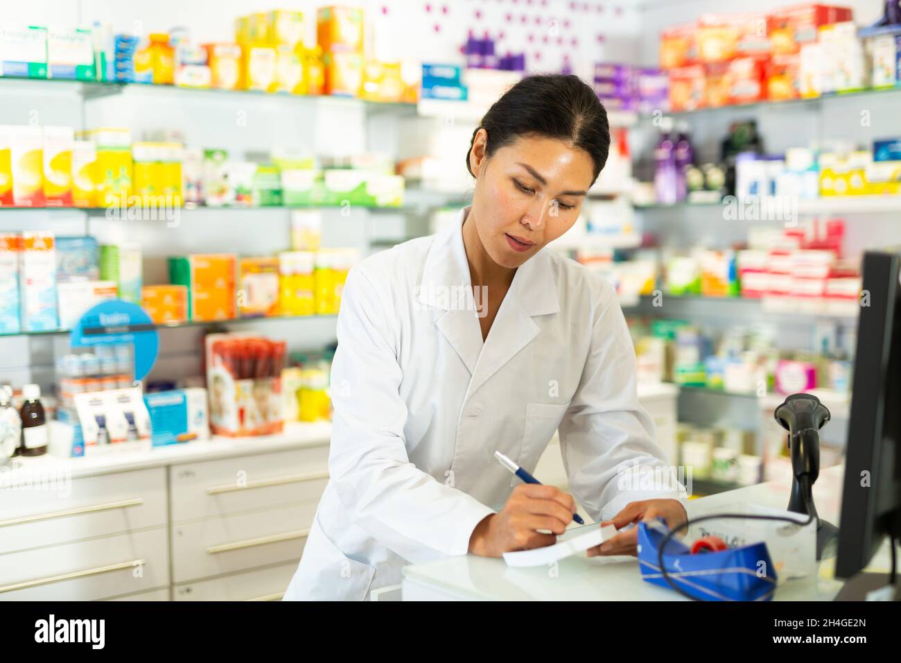 Female pharmacist writing recipe at counter Stock Photo - Alamy