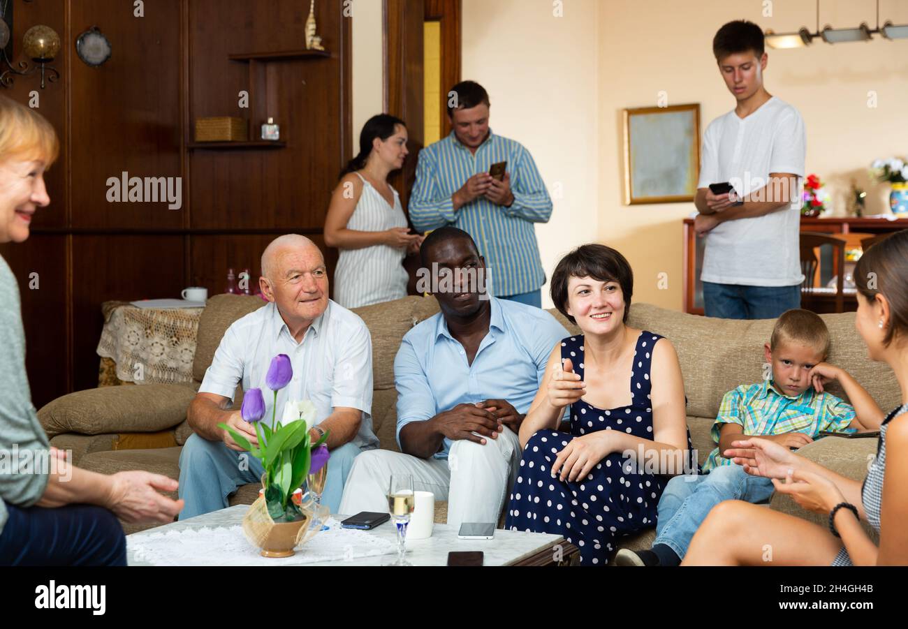 Multigenerational family chatting and drinking wine and tea at home ...