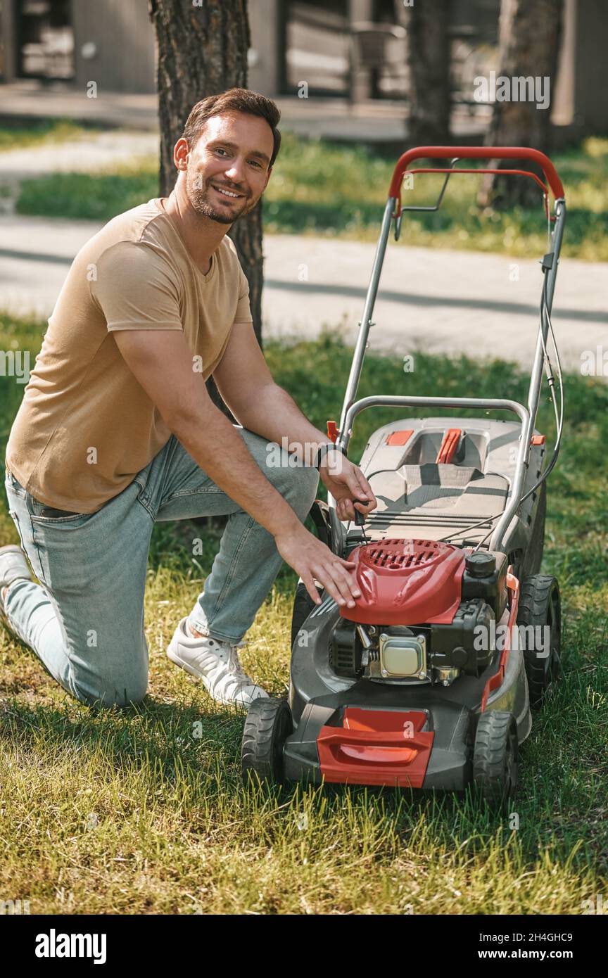 Smiling man turning on lawn mower Stock Photo - Alamy
