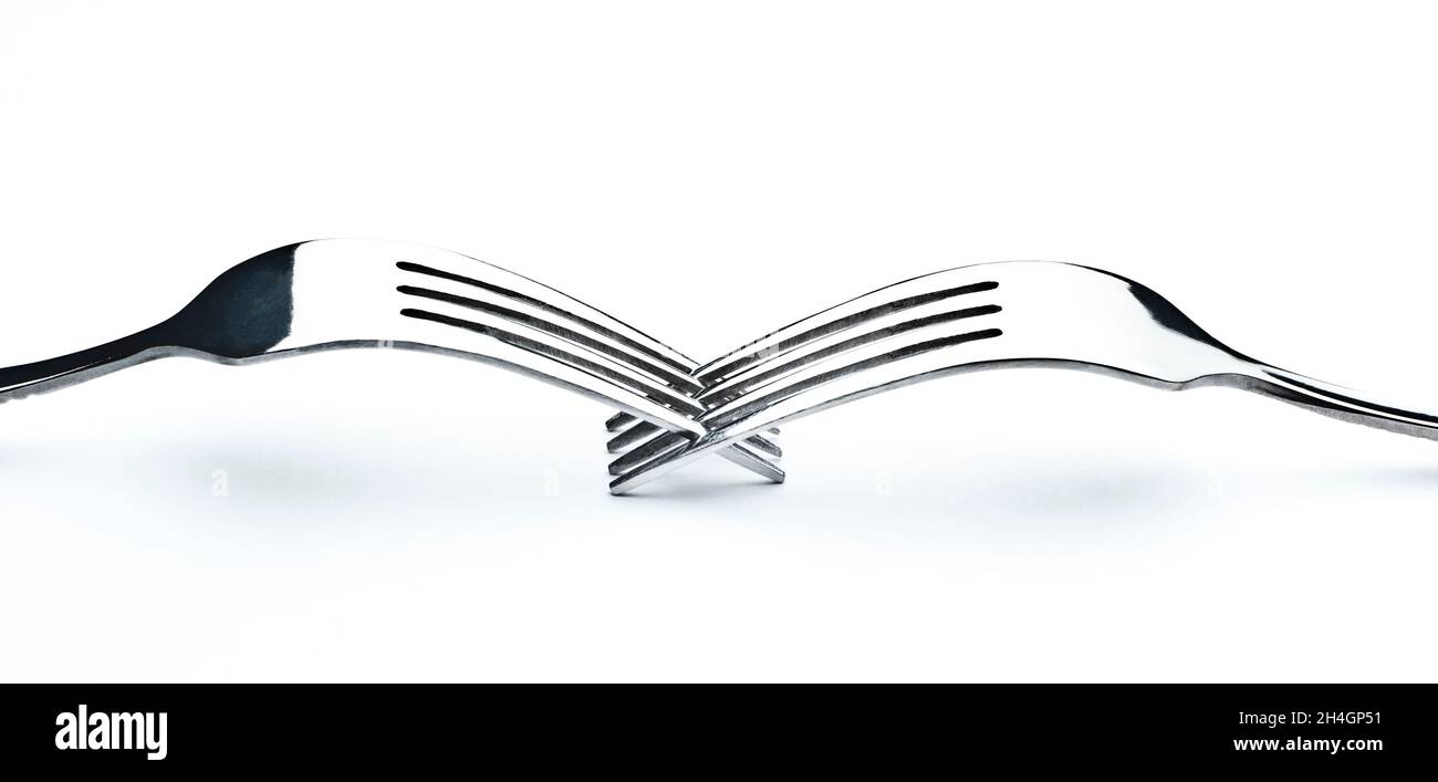 Two forks interwoven isolated on white background with subtle shadow ...