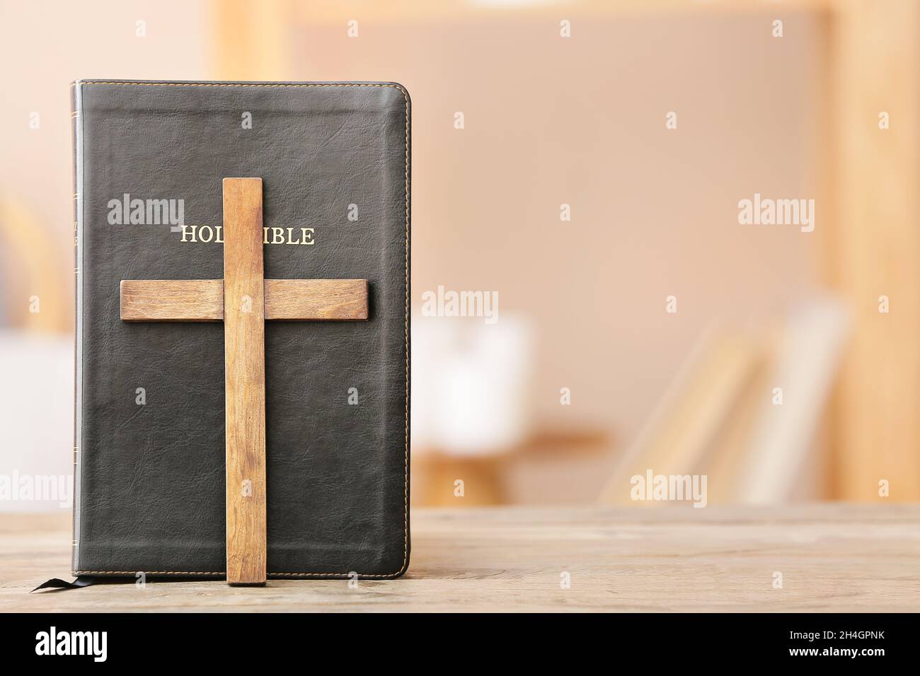 Holy Bible with cross on table in room Stock Photo - Alamy