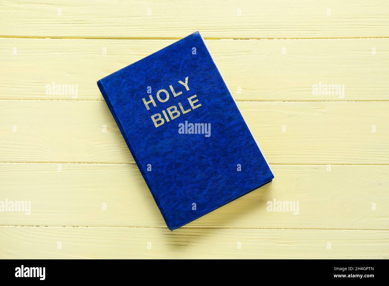 Blue Holy Bible on yellow wooden background Stock Photo - Alamy