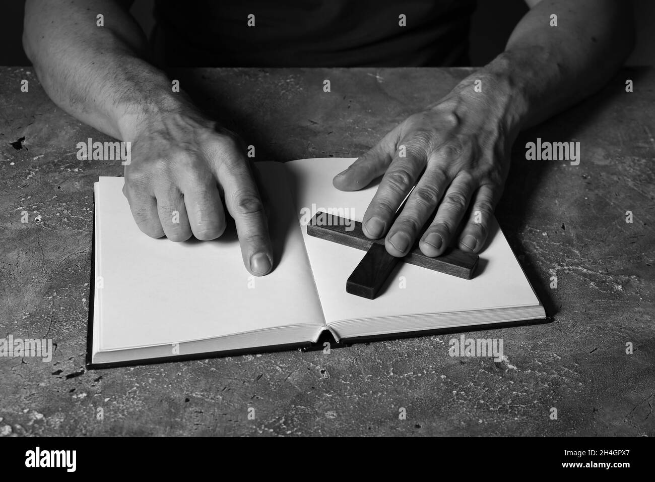 Man with cross reading Holy Bible at grunge table, closeup Stock Photo ...