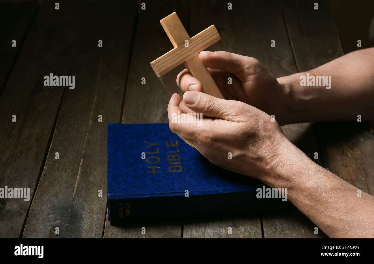 Man with cross and Holy Bible at dark wooden table, closeup Stock Photo ...