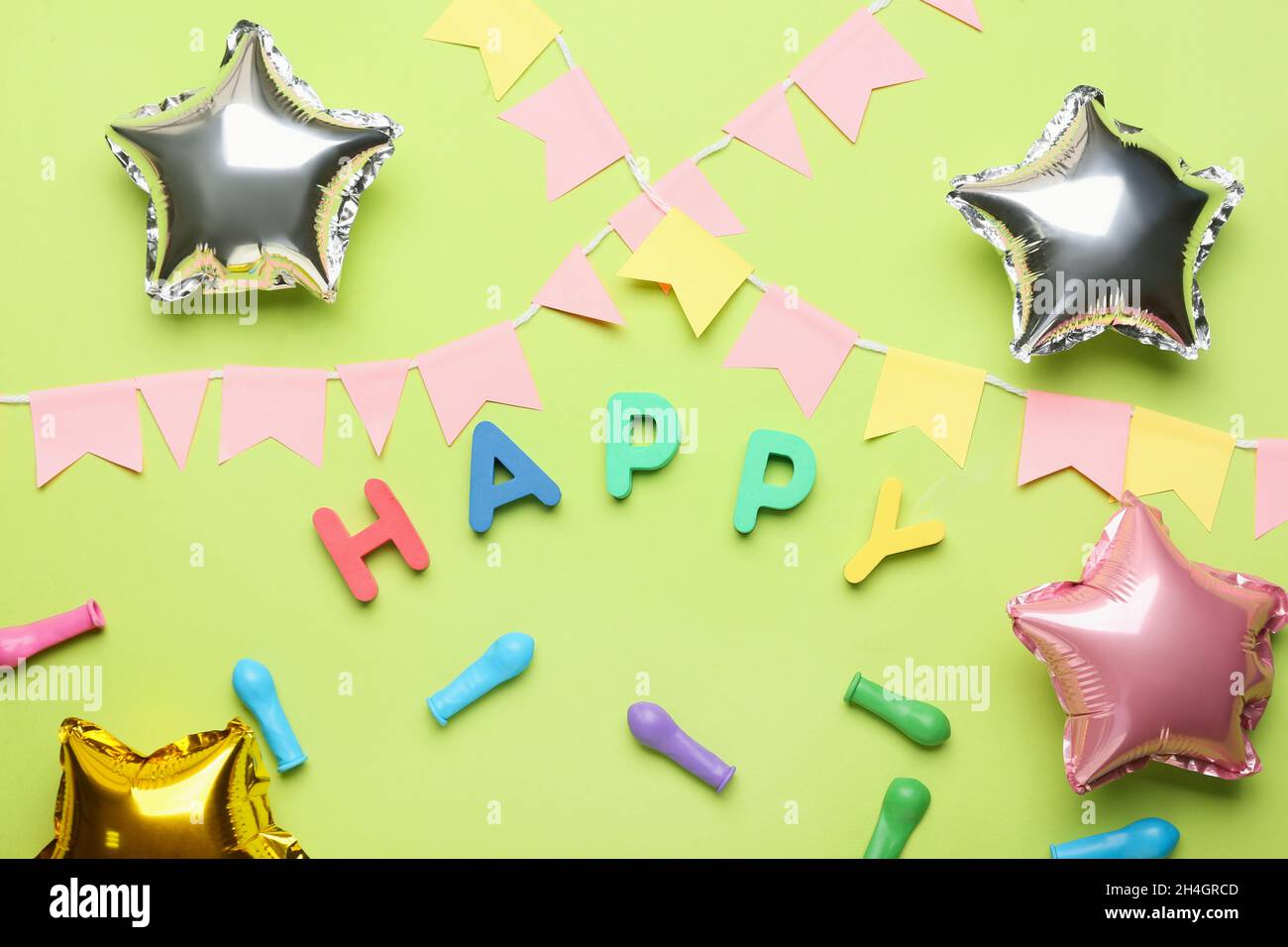 Composition with word HAPPY, balloons and garlands on green background ...