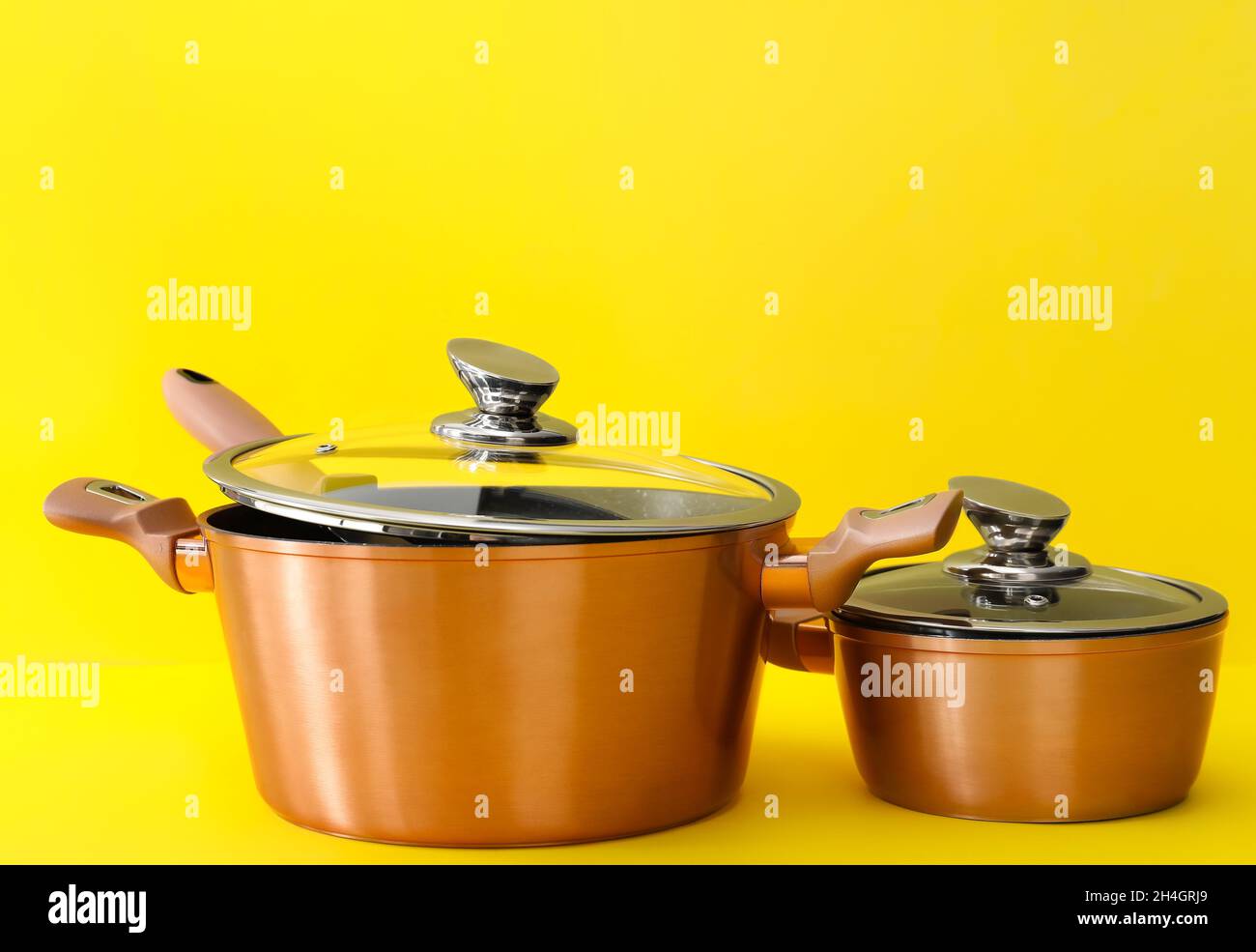 Cooking pots with glass lid on color background Stock Photo - Alamy