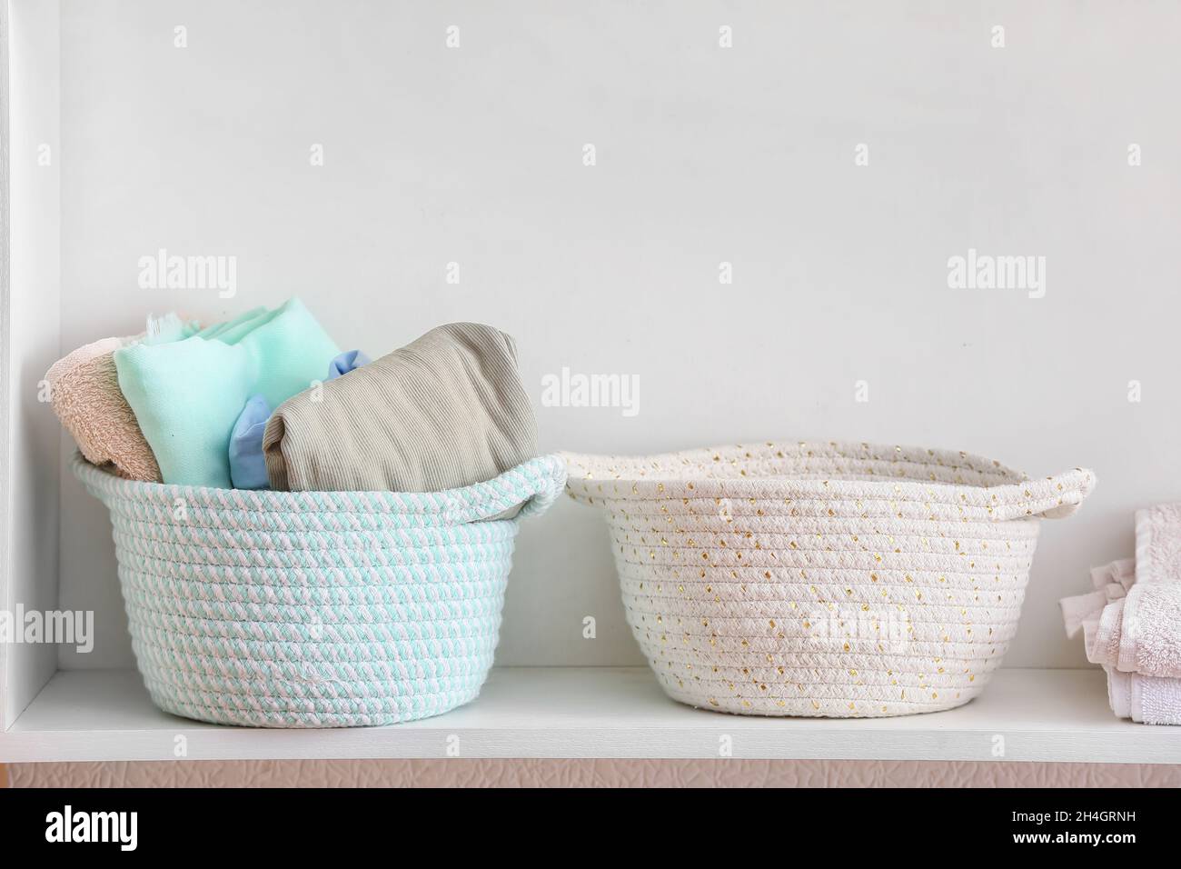 Baskets with clean clothes on shelf, closeup Stock Photo - Alamy