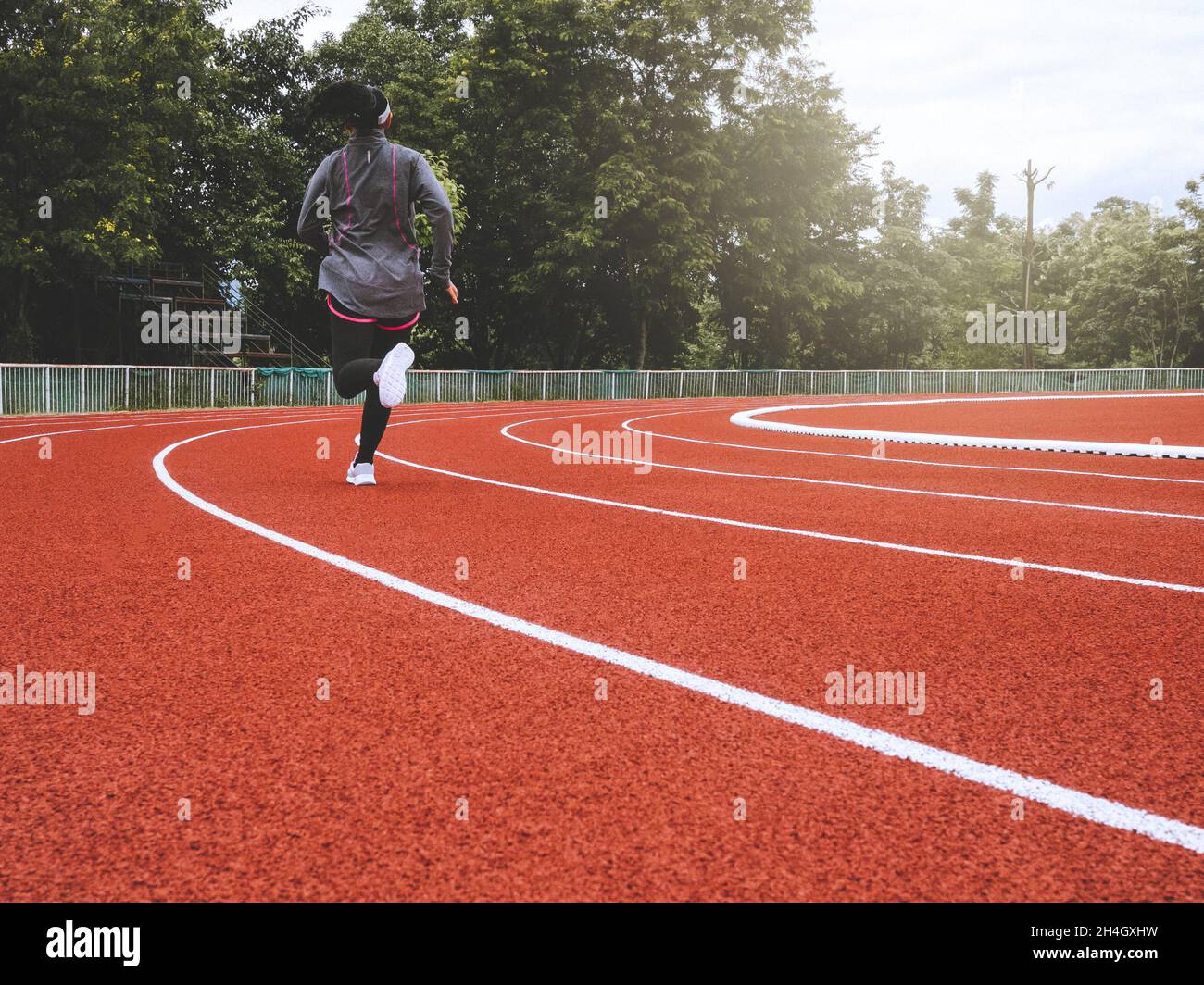Athletic woman in sport clothes running on stadium track. Female runner ...