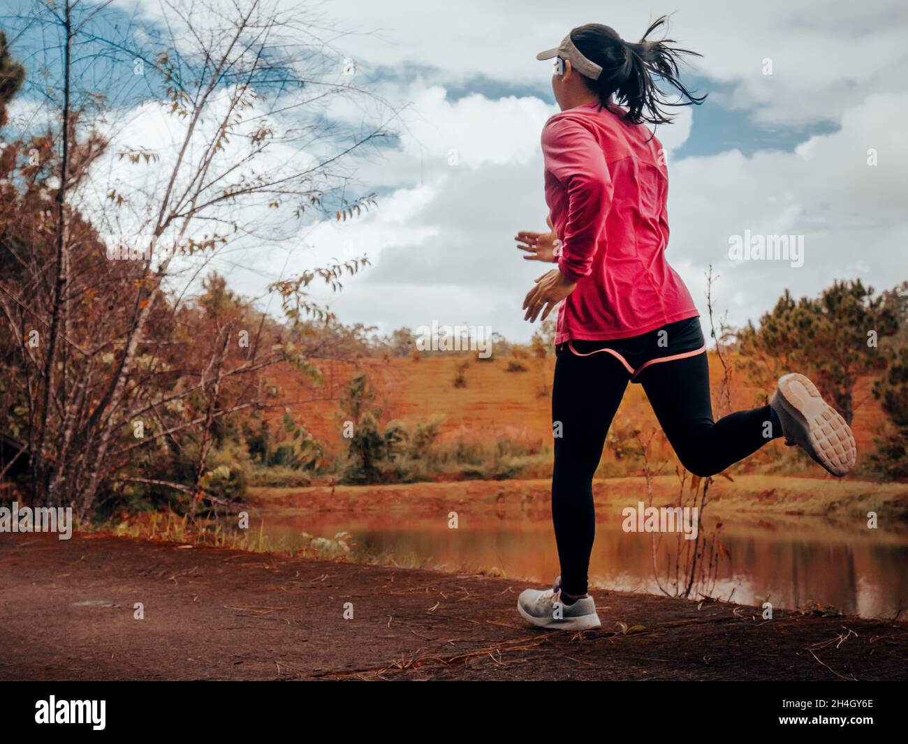 Athletic woman running on forest trail by the lake. Female runner ...