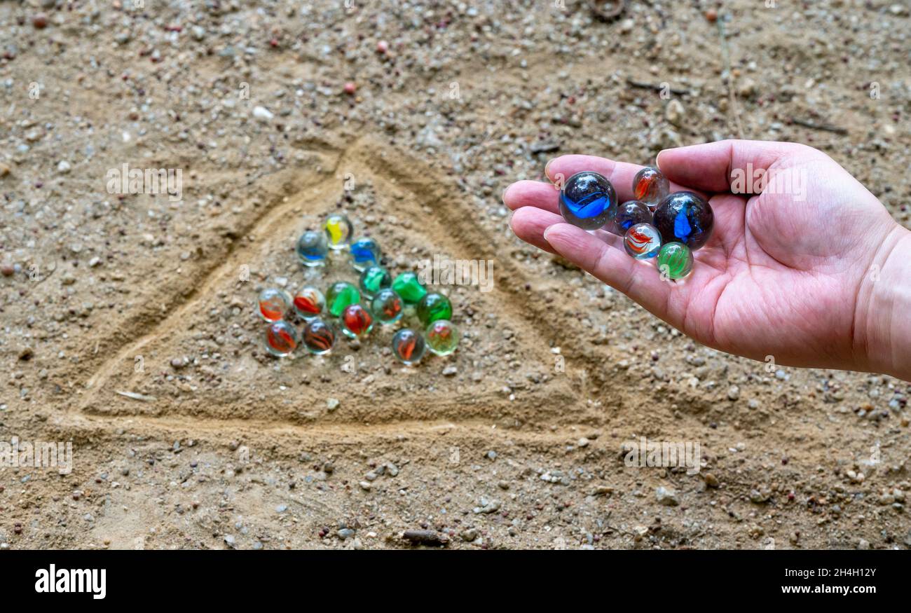 The hand of a man playing marbles in a playground with dirt Stock Photo ...