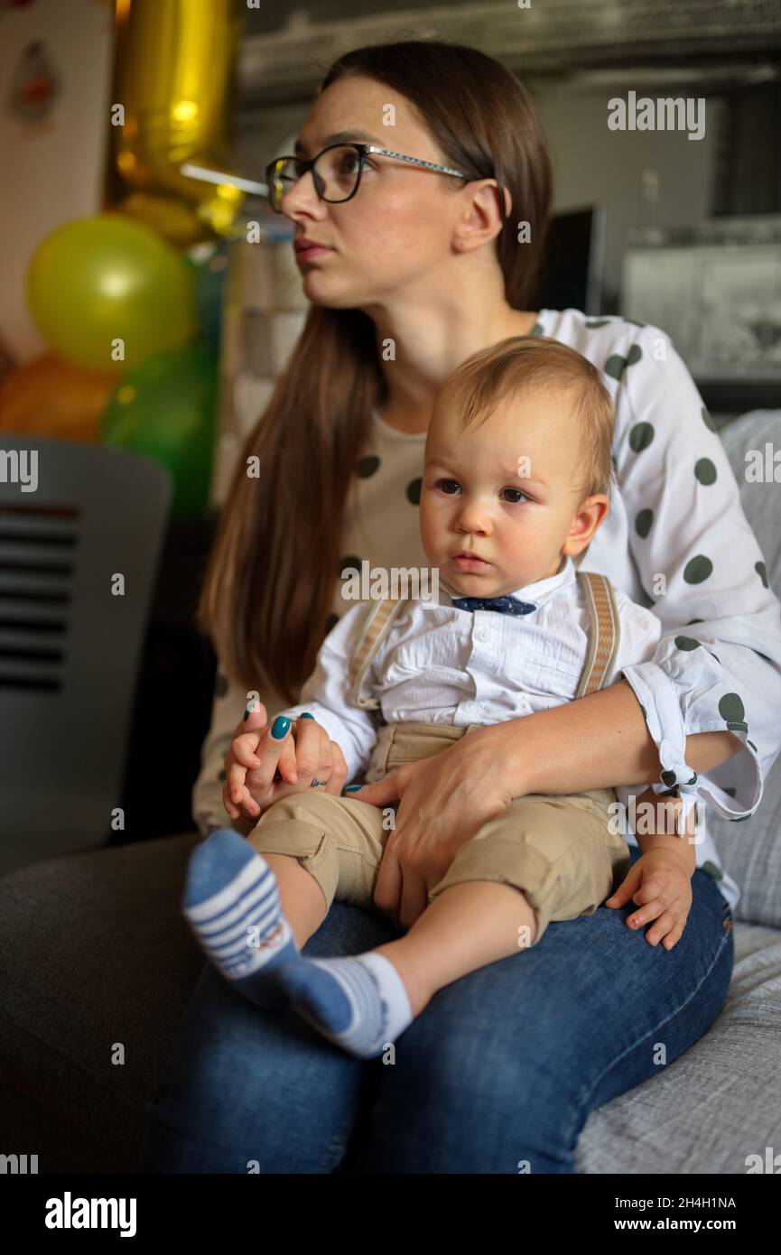 Mother sitting on a sofa and holding her cute little baby Stock Photo ...