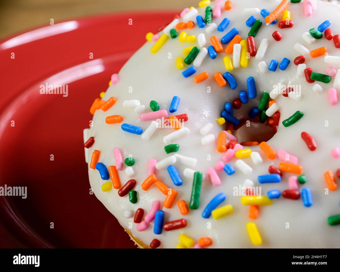 Donut with white icing and sprinkles Stock Photo - Alamy