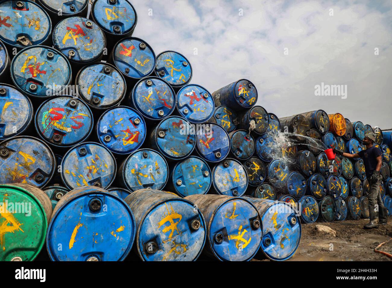 A worker seen washing empty oil drums for recycling at a warehouse in ...