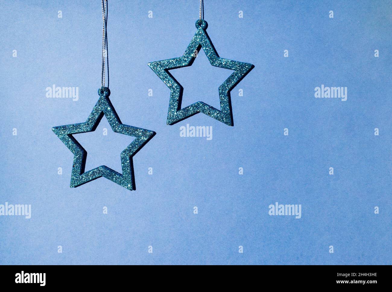Two blue shining stars on a light blue background. Copy space for text ...