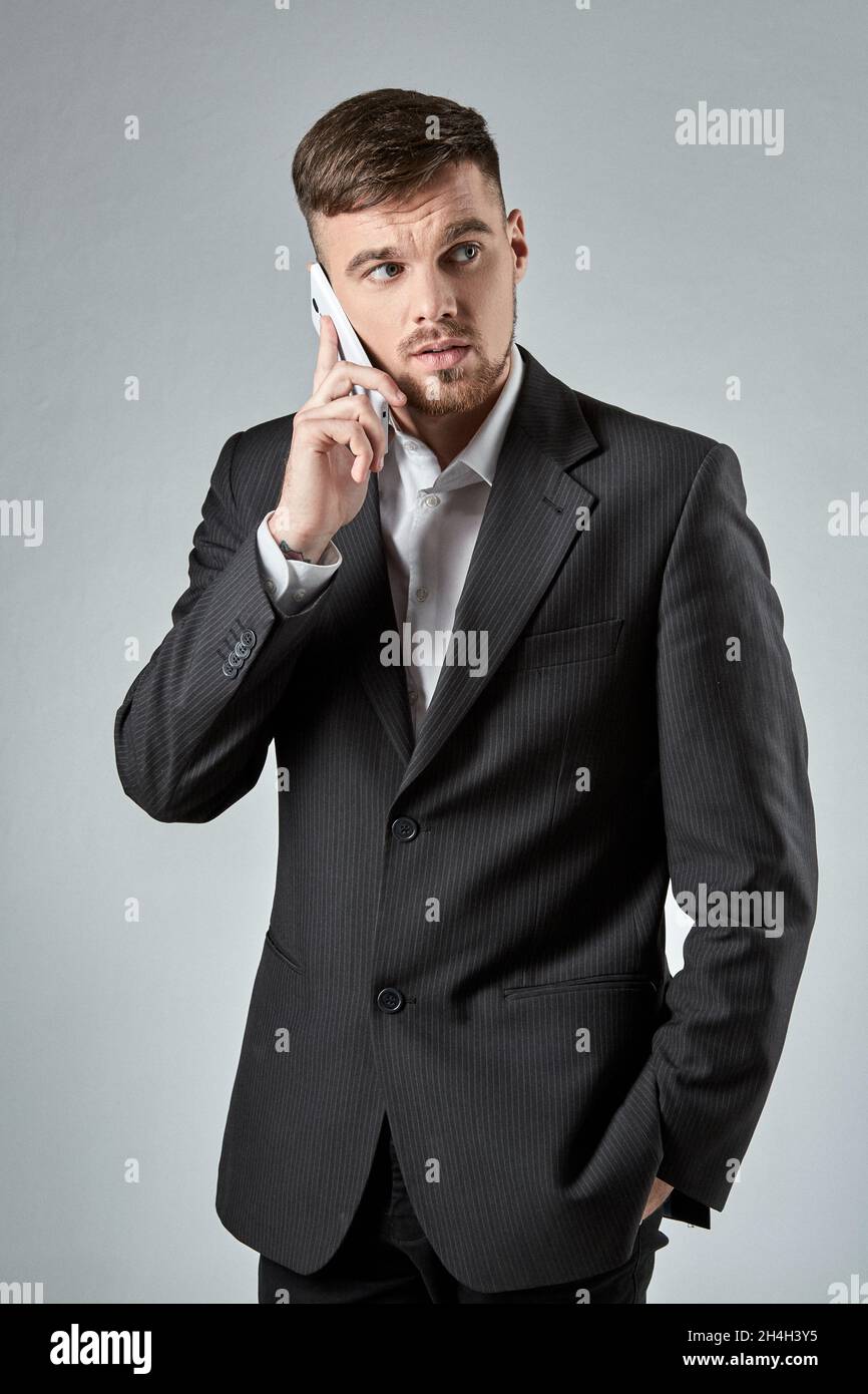 Portrait of a handsome businessman making phone call against grey ...