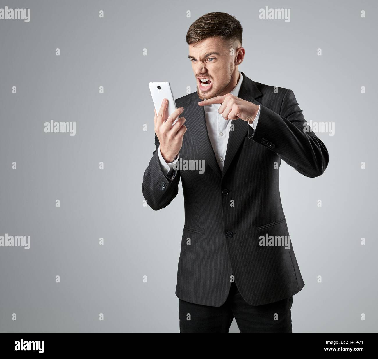 Portrait of a handsome businessman making phone call against grey ...