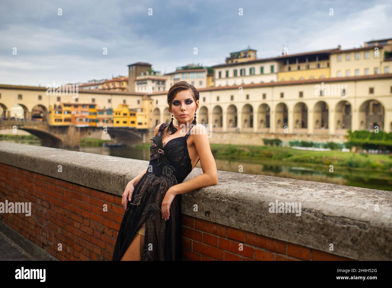 Beautiful stylish bride in a black dress stands on the embankment in ...
